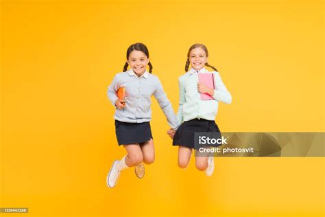 학교로 돌아오게 되어 기쁩니다 공중에 있는 초등학교 학생들 노란 배경에 책으로 점프 어린 소녀 학교 휴식 시간을 즐기는 작은