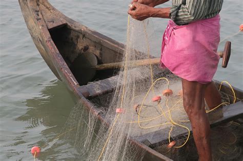 인도 어 부 작은 나무 낚시 보트 바다 잡기 작은 물고기 씨 캐치에 의해 손으로 흰색 나일론 낚시 그물에 당기는 위에 기대어 앉아 전통 핑크 룬 기 사 롱 둘리에 물고기