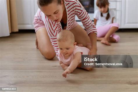 아이들과 함께 부엌에서 바닥에 앉아있는 줄무늬 캐주얼 스타일 셔츠를 입은 젊은 성인 여성 오븐 근처에 앉아있는 노인 아이 기어