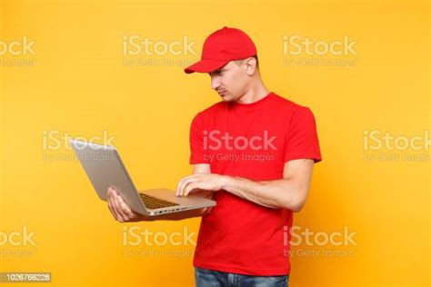 배달 사람 노란색 오렌지 배경에 고립입니다 빨간 모자 노트북 Pc 컴퓨터에 입력 작업을 들고 T셔츠에에서 전문 남성 직원 택배 서비스 개념입니다 광고에 대 한 공간을 복사