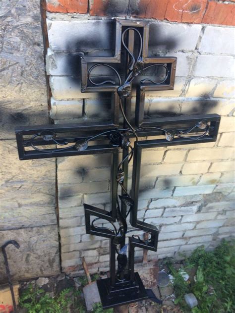 Металлический крест на фоне кирпичной стены