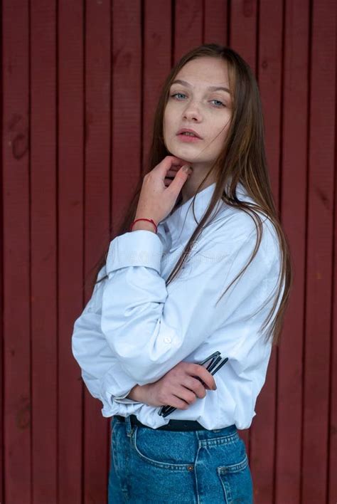 A Girl Posing Against A Red Background A Young Model In A White Shirt