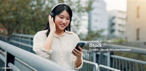 도시 행복한 여성 모바일 음악 스트리밍 팟캐스트 또는 여행을 위한 헤드폰 전화 야외 및 인터넷에서 오디오를 듣고 다리에서 온라인 라디오 앱에서 소리와 재즈 노래를 듣는 일본