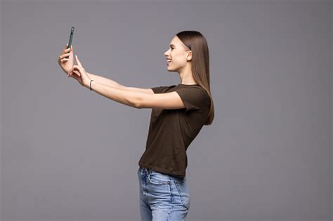 흰색 배경에 고립 된 스마트 폰에서 셀카 사진을 만드는 웃는 여성의 초상화 Brand Name Smart Phone에 대한 스톡 사진 및 기타 이미지 Brand Name