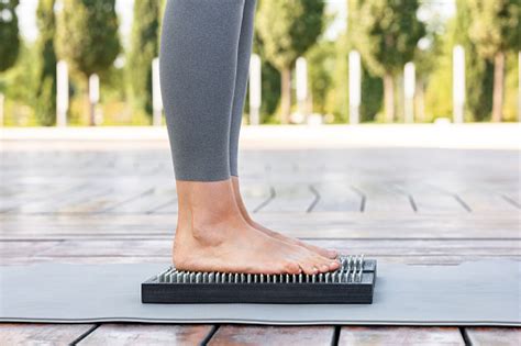 요가 수업 중 손톱이있는 나무 판에 맨발로 서있는 회색 바지를 입은 요기 여성 바늘 방석에 대한 스톡 사진 및 기타 이미지 바늘 방석 여자 Mental