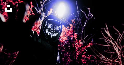 파란색과 흰색 공을 가진 나무 아래에 서 있는 흑백 까마귀를 입은 남자 사진 Unsplash의 무료 네온 이미지