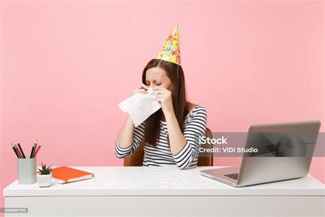 파티 모자 닦아 울고 했다는 여자 분홍색 배경에 고립의 노트북과 흰색 책상에 사무실에서 혼자 생일을 축 하 하기 때문에 조직으로