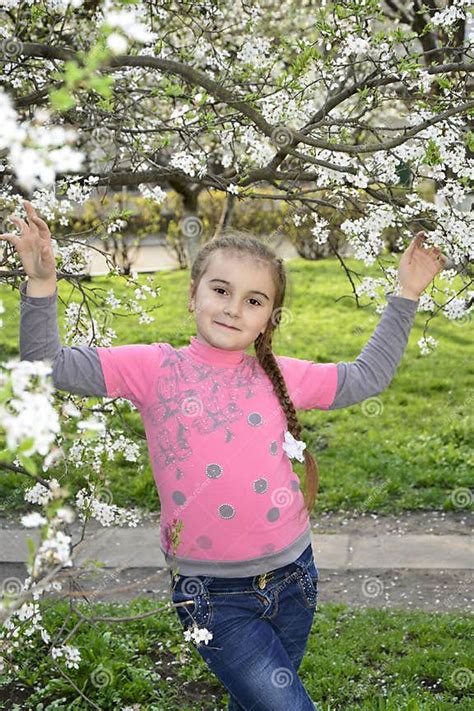 Salta No Jardim Uma Menina Que Guarda Um Ramo Da Cereja Foto De Stock Imagem De Fêmea Posse