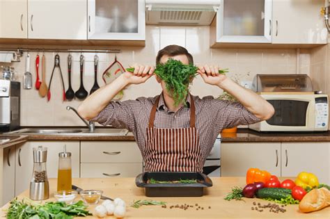 재미 있는 젊은 남자가 앞치마 테이블에 앉아 나무 표면 멋진 주방의 전체 빛 부엌에 돼지고기 쇠고기 또는 양고기 고기 스테이크를 준비 하는 가정에서 요리 딜 또는 회 향