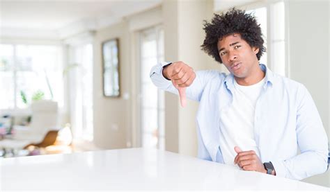 집에서 아프리카계 미국인 남자 보고 불행 하 고 화가 보여 거부 와 부정적인 엄지 손가락 아래로 제스처 잘못된 표현입니다 가정 생활에 대한 스톡 사진 및 기타 이미지