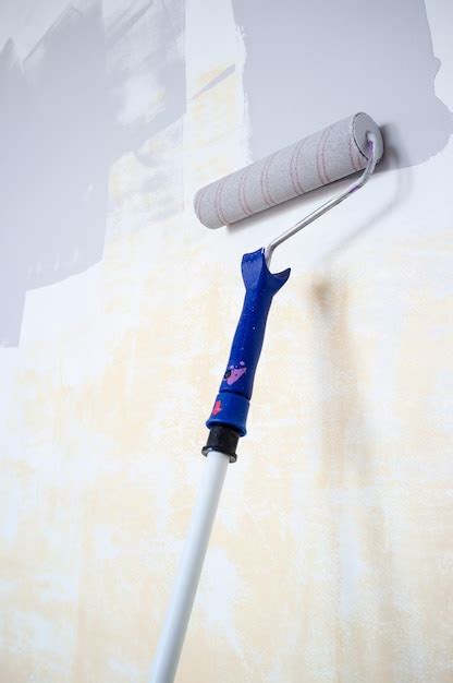 Premium Photo Roller On A Wooden Stick In Gray Paint Is Used To