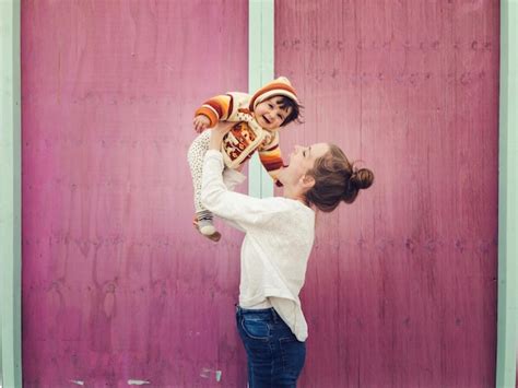 Premium Photo Mother Lifting Daughter While Standing Against Wall