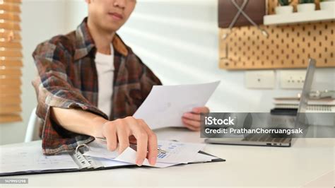 하얀 책상 위에서 서류를 들고 노트북을 사용하는 스타일리시한 남성 프리랜서의 사진 사람 기술 및 원격 근무 18 19세에 대한