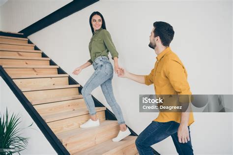 잘 생긴 남자와 그의 예쁜 여자의 전체 길이 프로필 사진 그냥 구입 현대 스타일 인테리어 평면 실내 캐주얼 옷을 입고 새로운 개조를 보여주는 계단을 올라가 계단에 대한 스톡