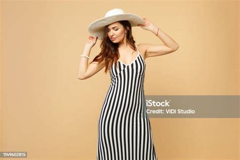 스튜디오에서 파스텔 베이 지 배경에 고립 된 보고 검은 색과 흰색 줄무늬 드레스 모자 서 매력적인 여자의 초상화 사람들은 진심으로 감정 라이프 스타일 개념입니다 복사 공간을