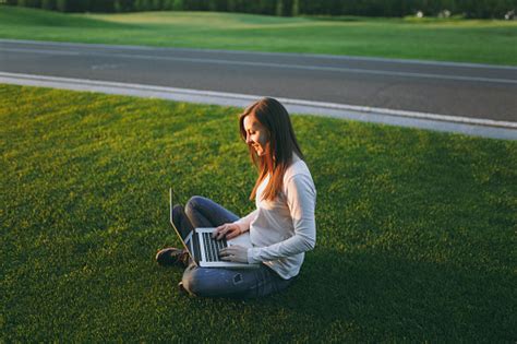 영 캐주얼 옷에 여성 학생 스마트 여자 잔디에 앉아 푸른 잔디 햇빛 잔디 야외에 도시 공원에서 노트북 Pc 컴퓨터에서 작업 모바일 사무실입니다 프리랜서 비즈니스 개념 개념에