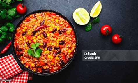 토마토 소스에 쇠고기 팥 파프리카 옥수수 고추를 곁들인 칠리 콘 카르네 요리 냄비에 매운 텍스멕스 요리 검은 테이블 배경 상위