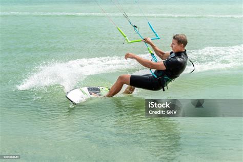 젊은 성인 백인 적합 남성은 바다 또는 바다 해안에서 푸른 하늘에 대한 밝은 화창한 날에 태양 자외선 보호 정장에 승마 연 서핑 보드를 즐길 수 있습니다 워터 스포츠