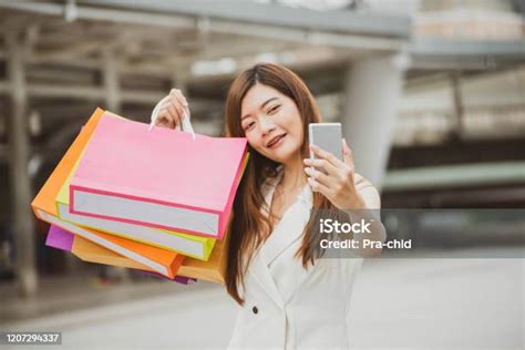 아시아 여자 들고 쇼핑 백 및 사용 스마트폰 에 쇼핑 온라인 가방에 대한 스톡 사진 및 기타 이미지 가방 개념 거리