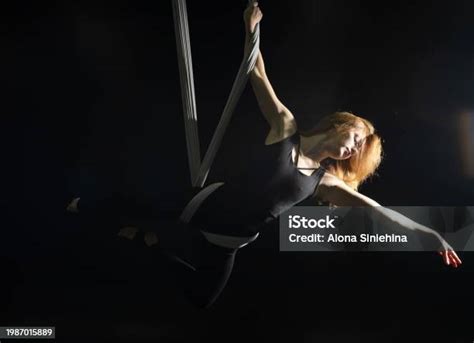 플라이 요가 검은 배경에 흰색 해먹에 있는 소녀가 공중 곡예를 보여줍니다 체조 서커스 돔 아래 빛과 그림자의 놀이가 연극 공연감을 연출합니다 스포츠 활동 30 34세에 대한