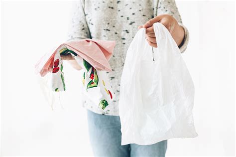 한 손에 들고 있는 여성은 재사용 가능한 에코 백 및 플라스틱 폴 리 에틸렌 봉지에 있는 다른 채소에 보관 합니다 플라스틱 무료 항목을 선택 합니다 금지 일회용 플라스틱