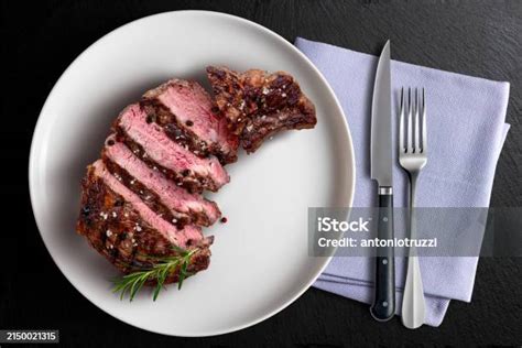 얇게 썬 갈비뼈 쇠고기를 나이프와 포크로 맛을 낸 흰색 둥근 접시에 담은 평면도 스테이크에 대한 스톡 사진 및 기타 이미지 스테이크 접시 고기 Istock