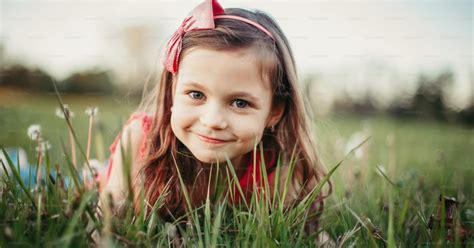 민들레 꽃 사이에 귀여운 사랑스러운 백인 소녀 초원의 풀밭에 누워있는 아이 야외 활동 여름 계절 어린이 활동 밖에서 즐거운 시간을 보내는 아이 행복한 어린 시절 생활