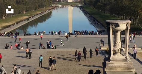 A Group Of People Standing Around A Reflecting Pool In The Middle Of A
