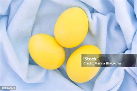 파란 천 위에 계란 3 개 머리 위 보기 세 개의 밝은 노란색 부활절 달걀이 구겨진 푸른 천 위에 놓여 있습니다 휴일에 창조적 인 장식 0명에 대한 스톡 사진 및 기타