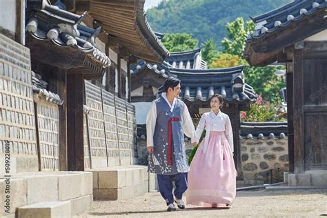 한복을 입고 전통 가옥 기왓장 담장과 서울의 남산을 배경으로 걷고 있는 아름답고 멋진 젊은 아시아 한국 남녀 모델 Stock Foto Adobe Stock