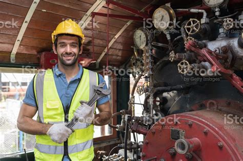 물 펌프장에 있는 남성 배관공 유지 보수 수도관의 초상화 남성 배관공 엔지니어는 직장에서 파이프를 수리하고 안전복 헬멧 장갑을 착용하고 있다 기계류에 대한 스톡 사진 및