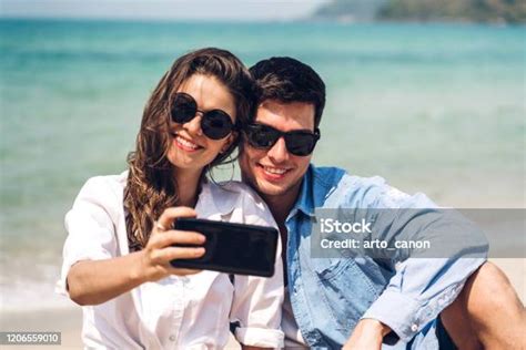 로맨틱 한 연인 젊은 부부는 열대 해변에서 함께 휴식 남자와 여자는 스마트 폰으로 셀카를 찍고 인생을 즐길 수 있습니다 여름 방학 바다에 대한 스톡 사진 및 기타 이미지