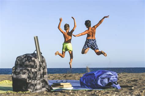 해변에서 행복 하 게 뛰어 다니는 학생 들은 학교의 끝을 축 하 합니다 바다 근처에서 놀고 있는 두 명의 흥분 한 소년의 자유와 행복의 개념 여름 방학 입욕을 즐기는 스쿨