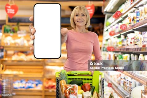 슈퍼마켓에서 쇼핑하는 미소 짓는 노인 여성 스마트 폰 모형 슈퍼마켓에 대한 스톡 사진 및 기타 이미지 슈퍼마켓 형판 휴대전화 Istock