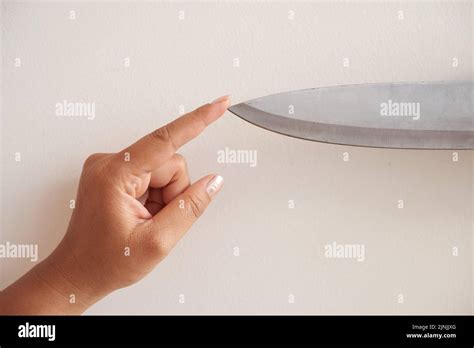 Close Up Shot Of Unrecognizable Woman Touching Tip Of Knife Isolated On White Background Stock