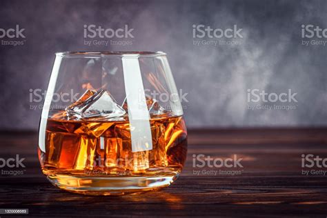 어두운 갈색 나무 테이블에 위스키 한 잔 얼음이 있는 투명한 노란색 알코올 음료 브랜디 버번 강한 알코올 음료 텍스트 템플릿을