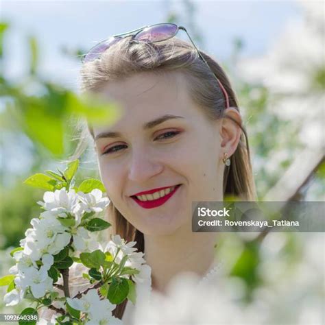 흰색 가기와 선글라스에 화창한 날에 피 사과 나무 가운데 머리 서 있는 아름 다운 젊은 여자의 초상화 개화기에 대한 스톡 사진