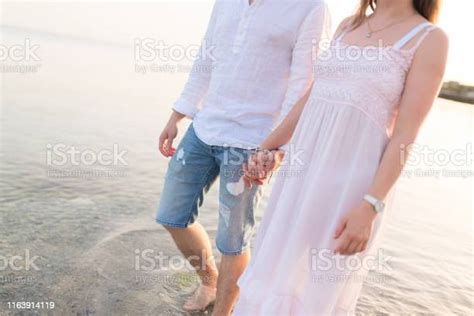손을 잡고 바다 해안을 따라 걷는 낭만적 인 젊은 부부의 야외 샷 젊은 남자와 여자는 일몰에 함께 해변에서 산책 몸 클로즈업 개념에 대한 스톡 사진 및 기타 이미지 Istock