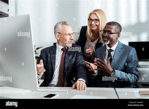 Happy Blonde Woman In Glasses Showing Thumb Up Near Multicultural