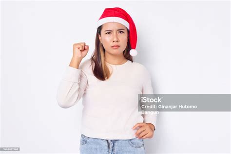 산타클로스 모자를 쓴 매력적인 젊은 아시아 여성이 먼저 손을 움켜쥐고 있다 흰색 배경 위에 고립된 카메라에 화난 표정 12월에