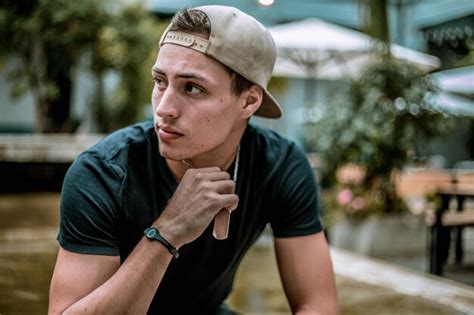 Premium Photo Thoughtful Young Man Wearing Cap While Sitting Outdoors