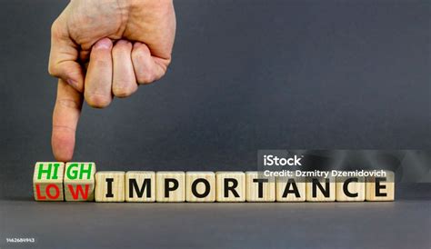 중요도가 높거나 낮은 기호입니다 개념 단어 나무 큐브에 높은 중요도와 낮은 중요성 사업가 손 아름 다운 회색 배경입니다 비즈니스 중요도가 높거나 낮은 개념입니다 공간을