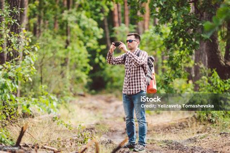 숲에서 사진 스마트 폰을 복용 하는 남자 하이커 휴대 전화로 사진을 만드는 매력적인 여행자 자연에서 배낭 하이킹을 하는 여행자 등산객 남자 관광 배낭 카메라를 사용 하 고
