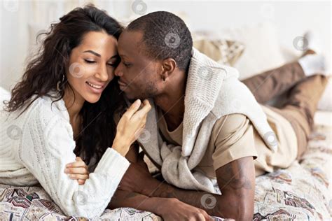 Влюбленная пара чернокожий мужчина и мулатка на кровати в светлой комнате Разнообразная семья
