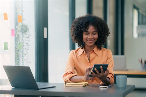 젊은 아프리카 계 미국인 사업가가 계산기를 들고 사무실 책상에서 컴퓨터로 일하고 있습니다 20 24세에 대한 스톡 사진 및 기타