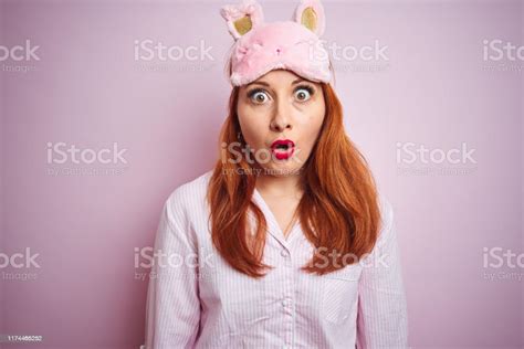 분홍색 고립 된 배경에 잠옷을 입고 젊은 아름다운 빨간 머리 여자는 두려워하고 깜짝 표정 두려움과 흥분 얼굴로 충격 감정에 대한 스톡 사진 및 기타 이미지 Istock