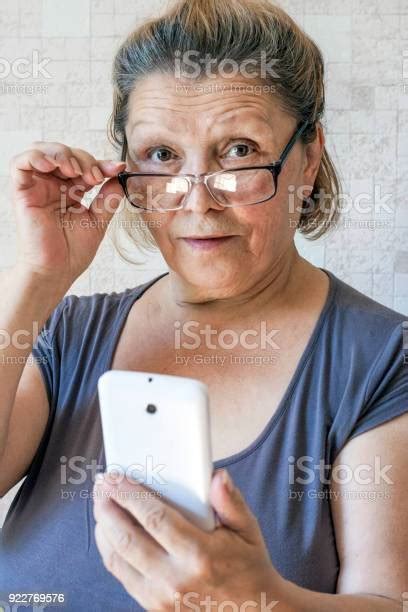 유리를 통해 카메라에 보이는 그녀의 손에 휴대 전화를 가진 노인 숙 녀 80 89세에 대한 스톡 사진 및 기타 이미지 80 89세 나이 노인 Istock