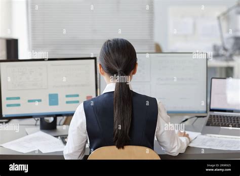 Back View Of Woman Working As Female Engineer Using Computer With Blueprints On Screens Copy