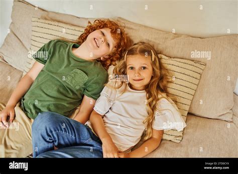Top View Of Brother And Sister Lying On Bed With Soft Pillows And