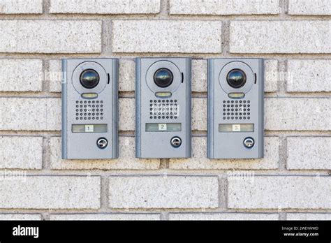 Three Intercom On White Textured Brick Wall Close Up Apartment Numbers And Push Button Door